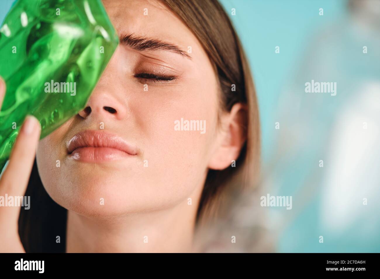 Close up depressed girl sadly covering face with empty plastic bottles ...