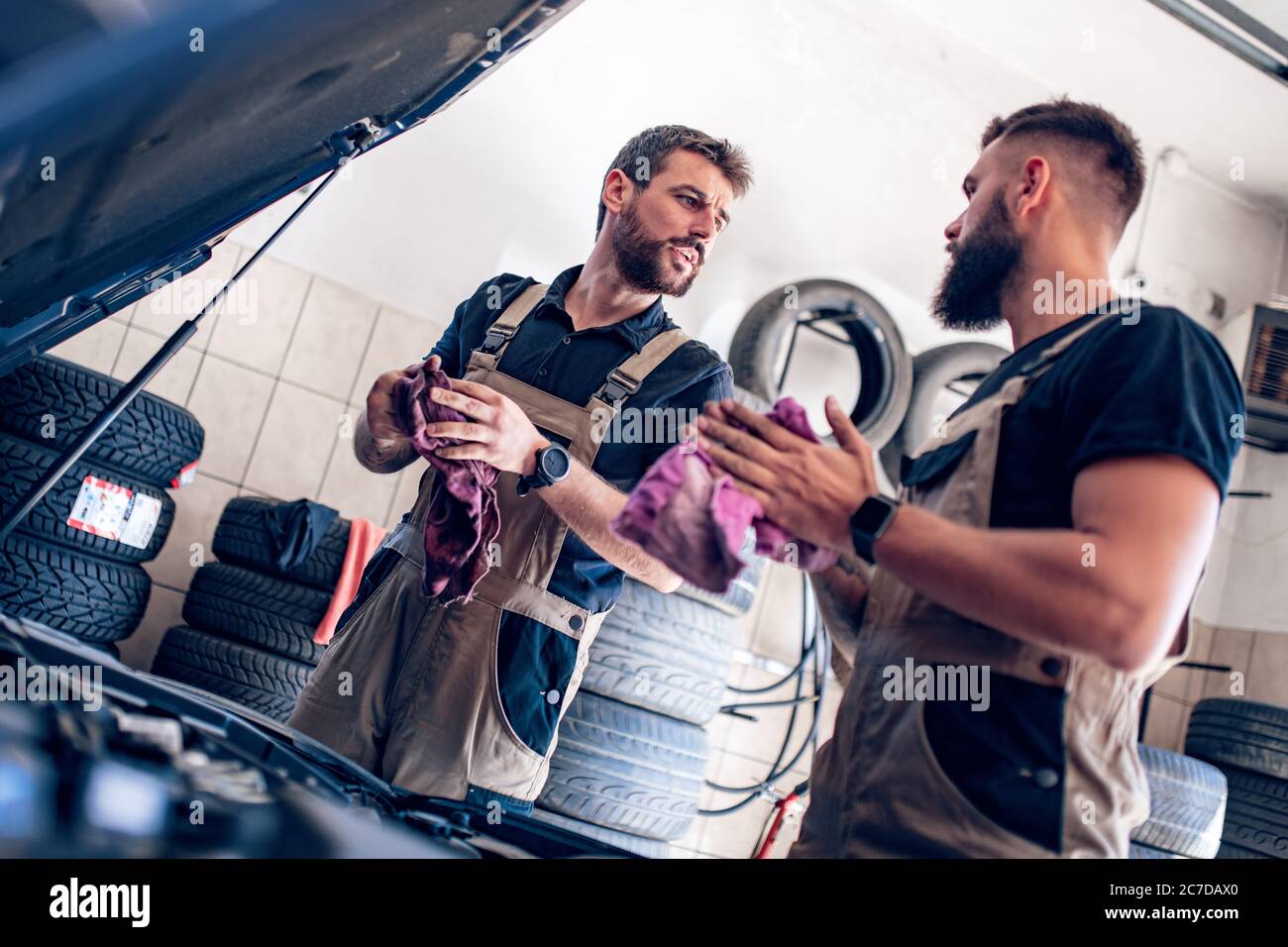 Auto mechanics cleaning his hands after repairing car engine in a ...