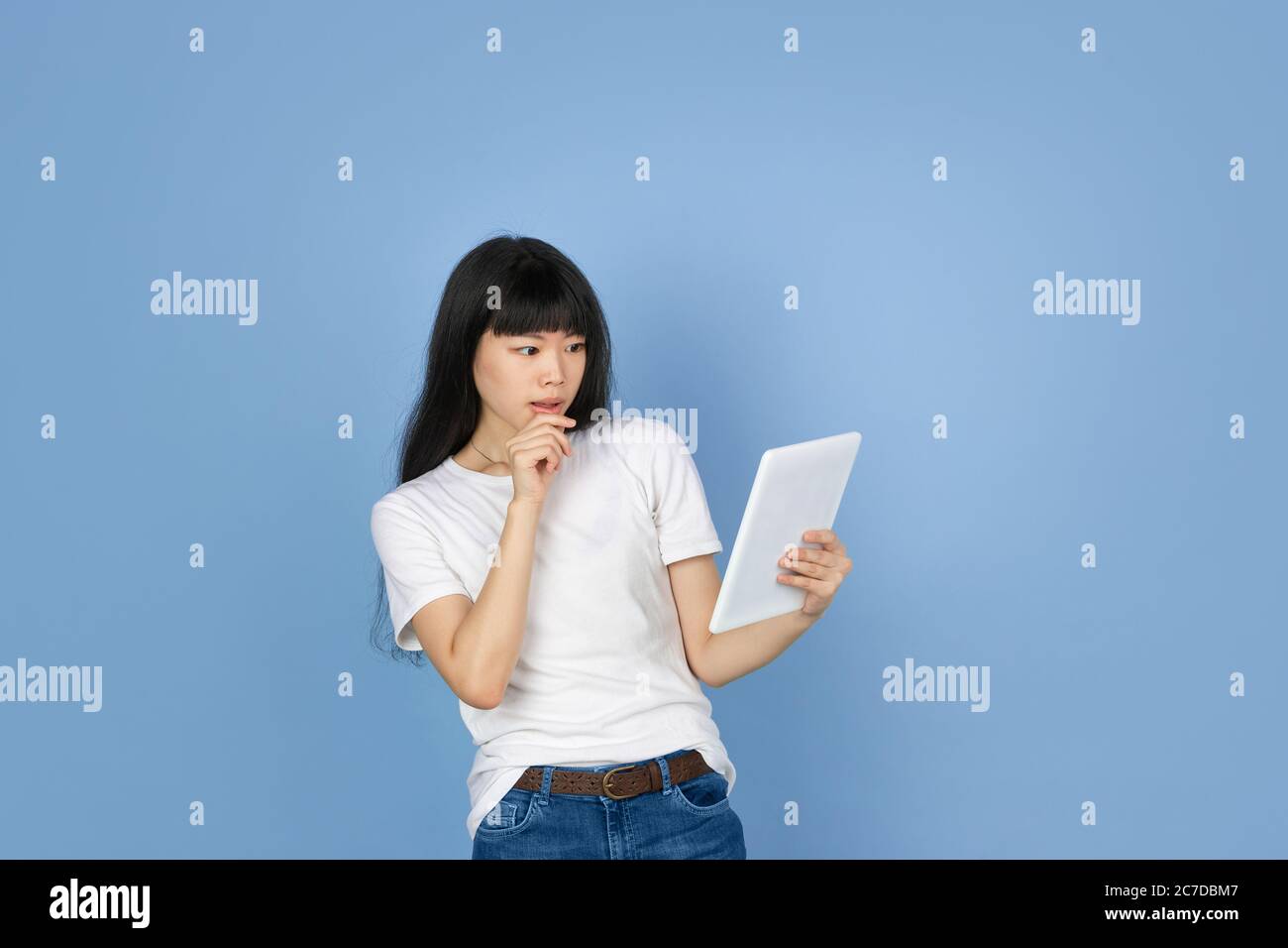 Scrolling tablet, surfing. Portrait of young asian woman isolated on ...