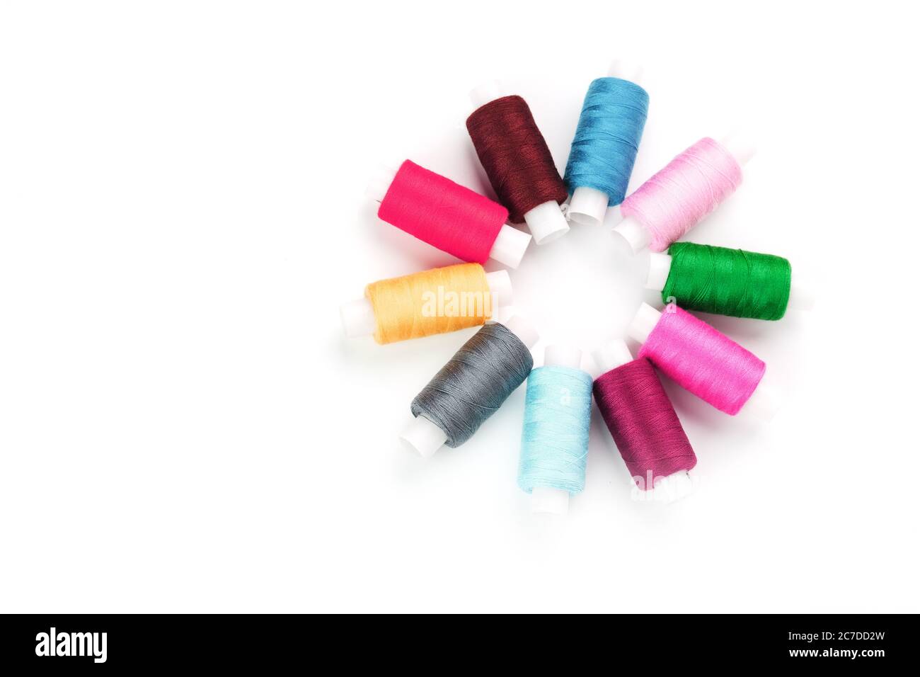 Sewing threads of different colors on reels on a white background in a ...