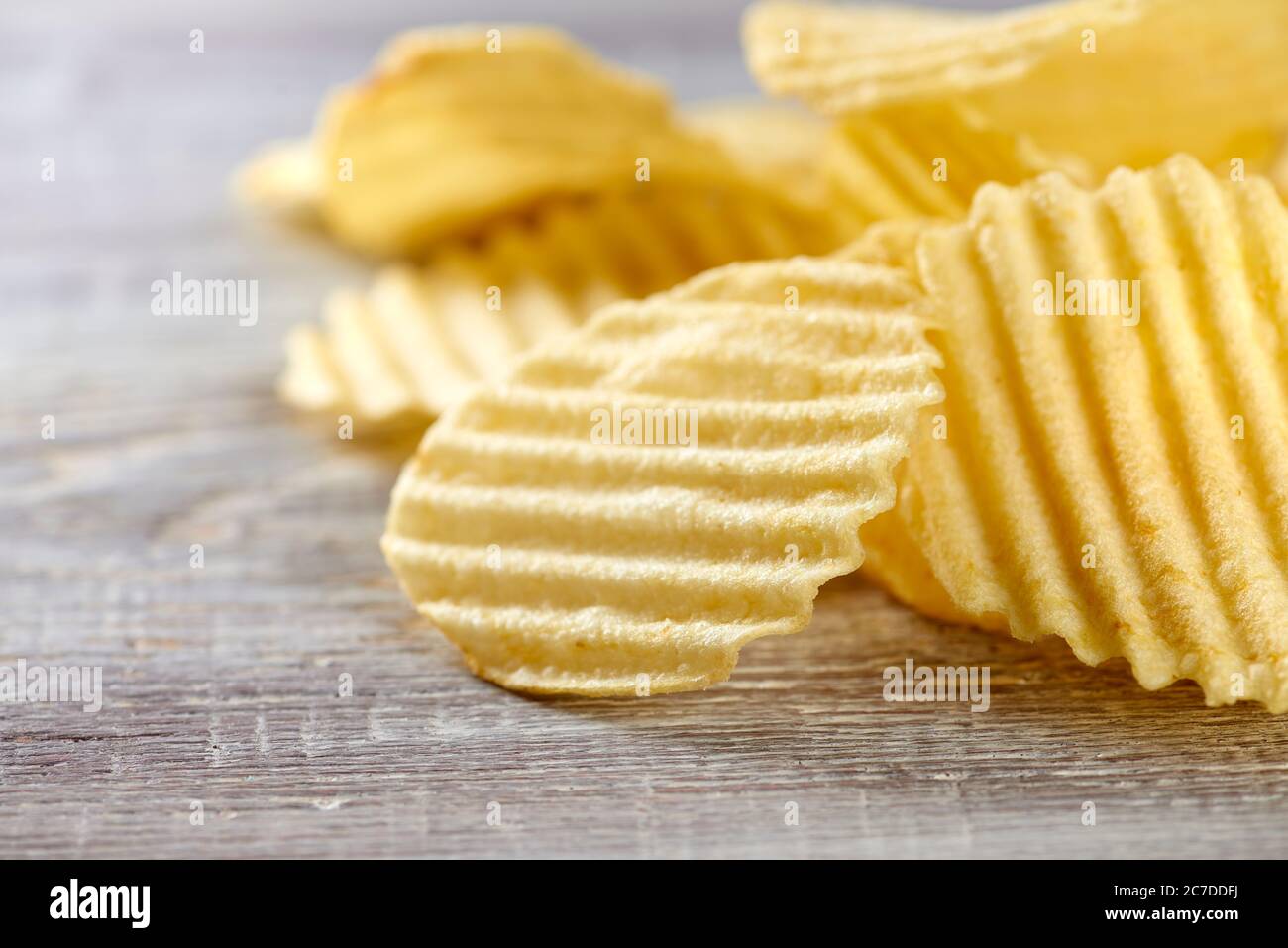 A pile of temptingly crunchy potato chips lies on the table. Junk food ...