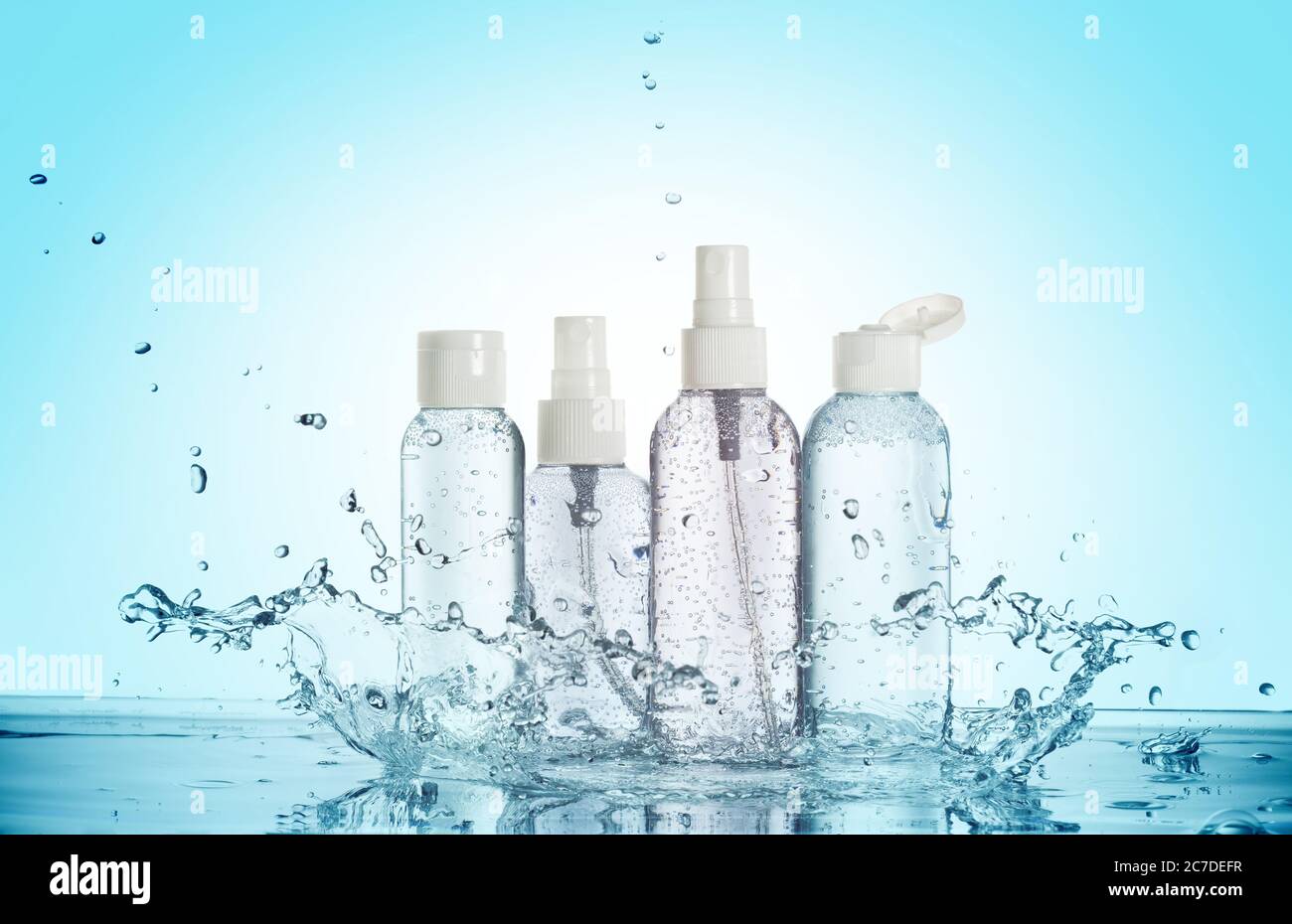 bottles of beauty products in a water splash isolated on blue ...
