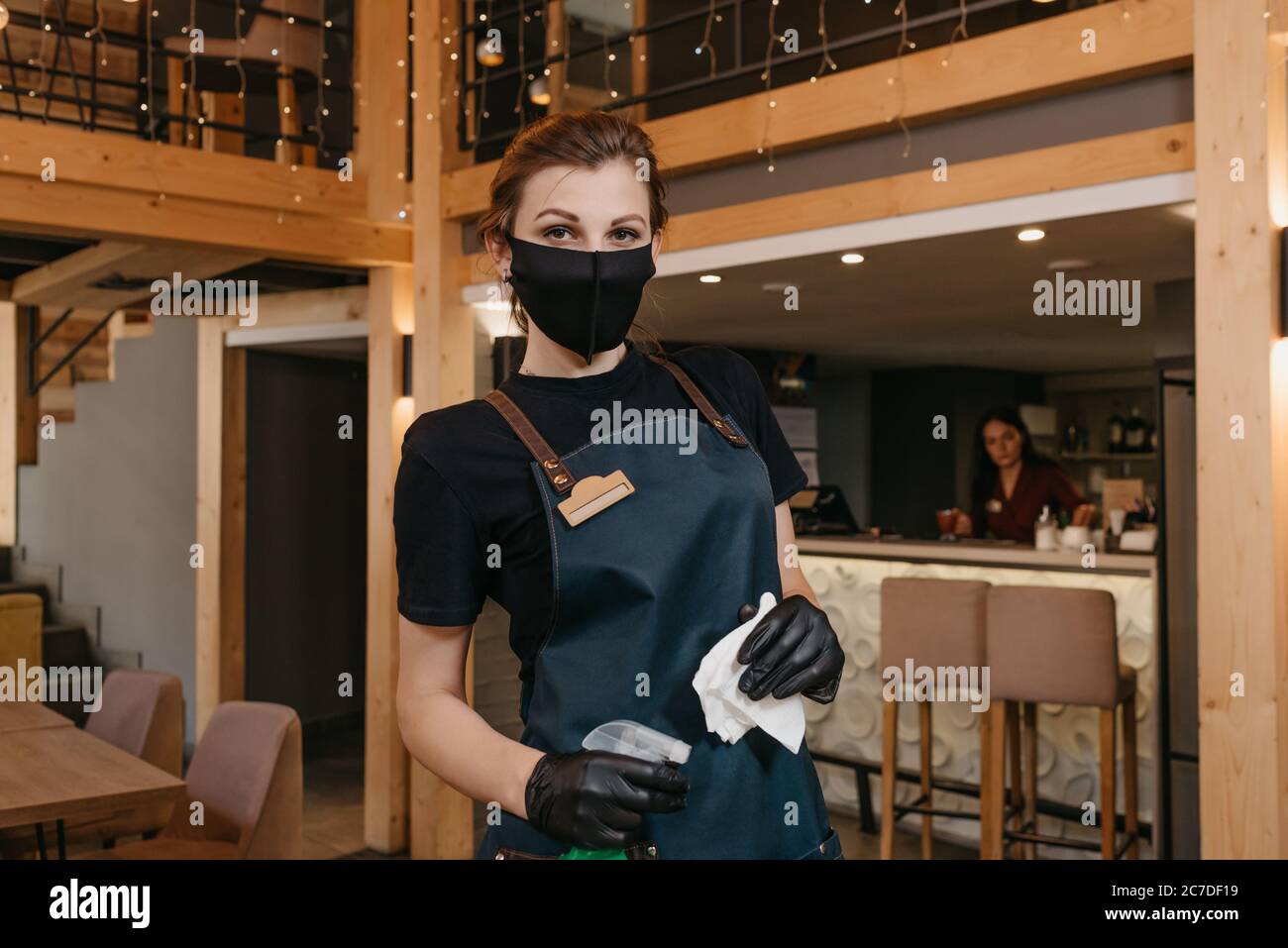 A close portrait of a stylish waitress who wears an apron, a black ...
