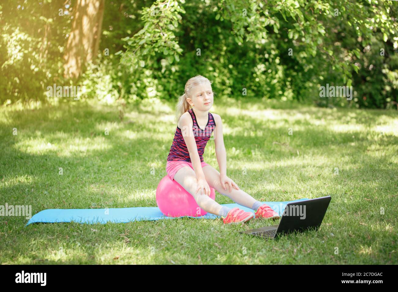 Caucasian girl child doing sport workout outdoor online. Video yoga ...
