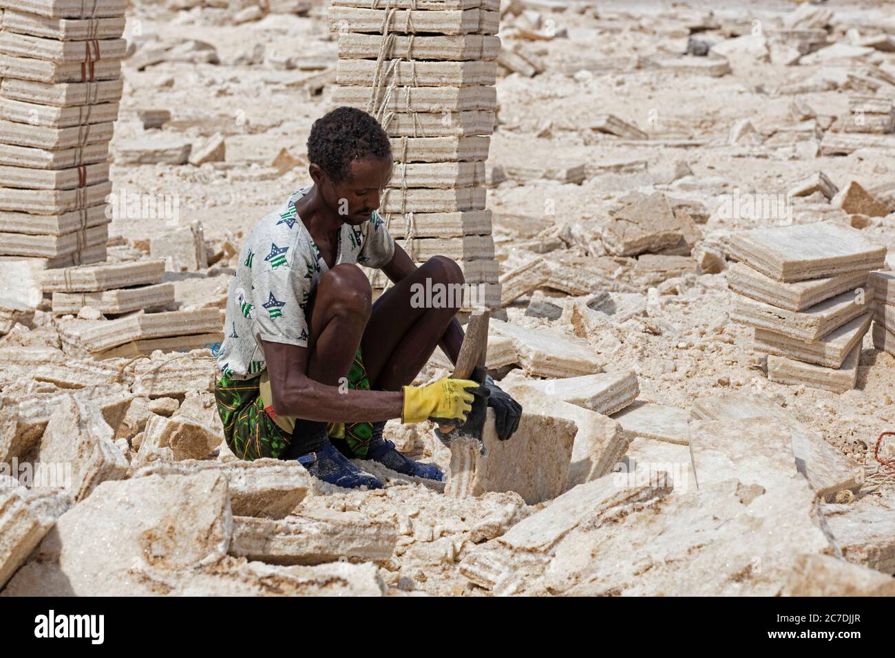 Afar salt miner at salt mine in salt flat chopping blocks / tiles ...