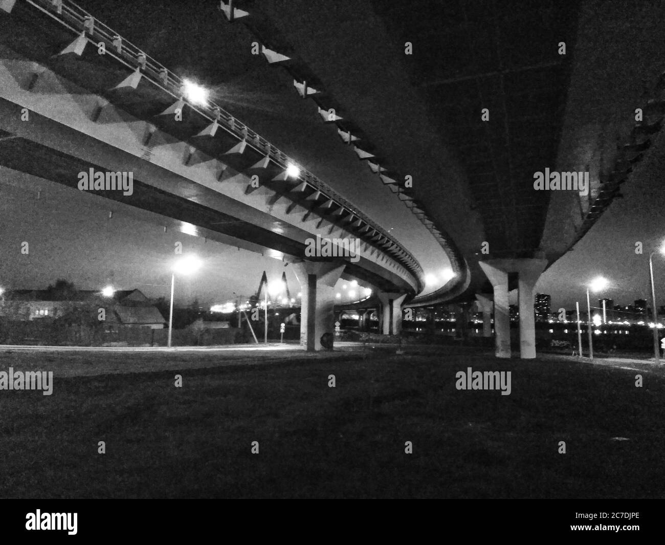 Low angle greyscale shot of a highway with columns surrounded by street ...