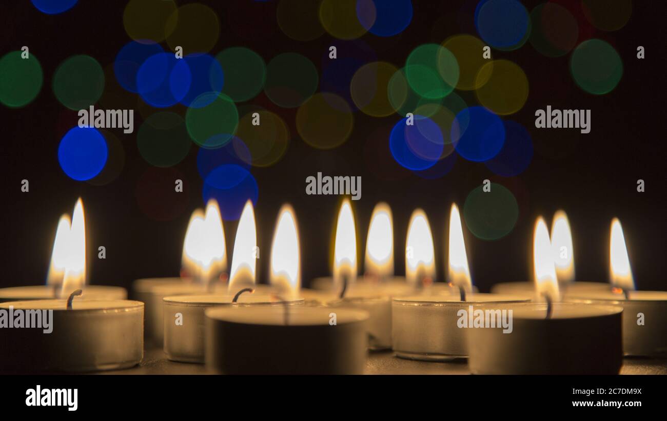 Tiny candles igniting together in the dark with lights shining in the ...