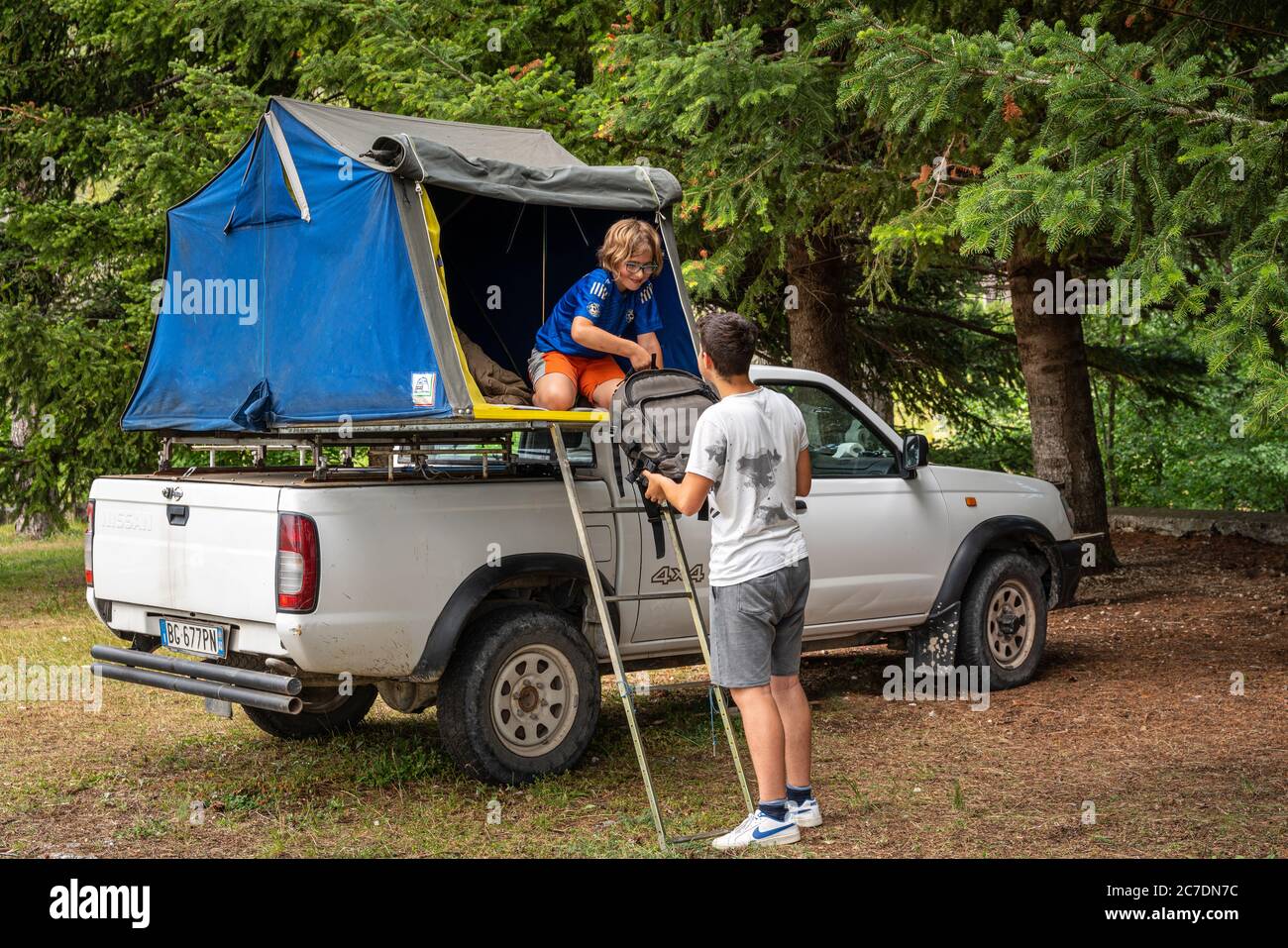 authentic two young people unload backpack from Car camping tent on the ...