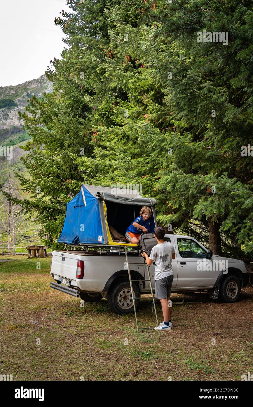 authentic two young people unload backpack from Car camping tent on the ...