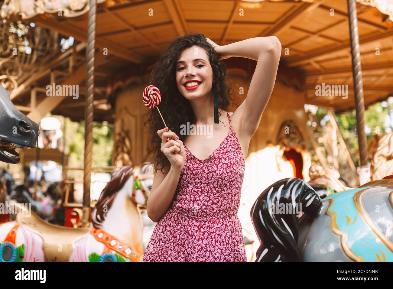 Beautiful lady with dark curly hair in dress standing with lolly pop ...