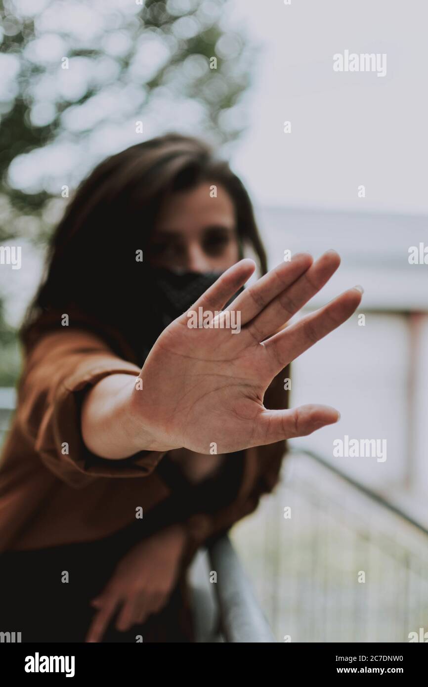 Vertical selective shot of an insecure female with covered mouth ...