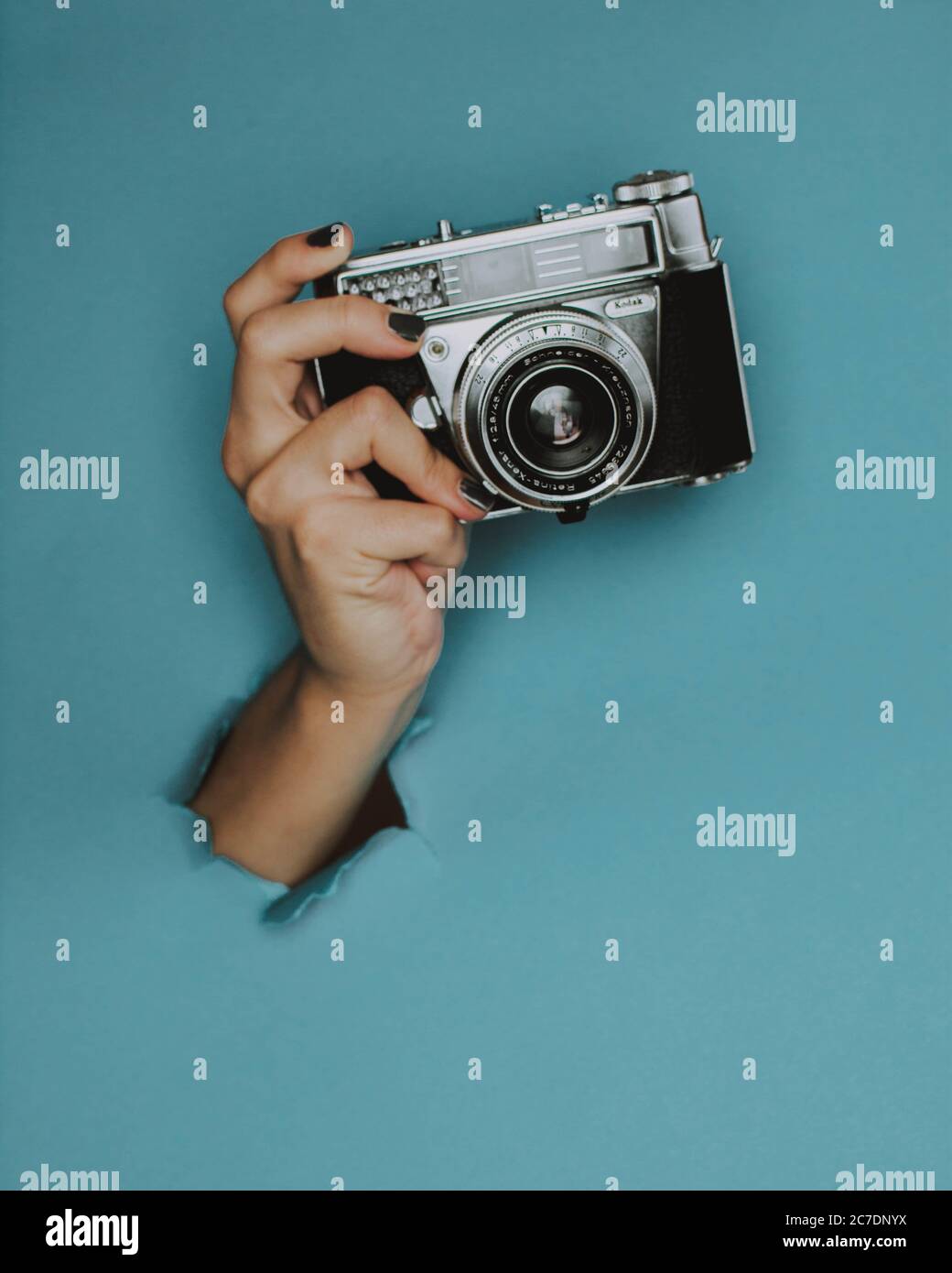 Vertical shot of a hand coming out of a blue wall hole holding a black ...