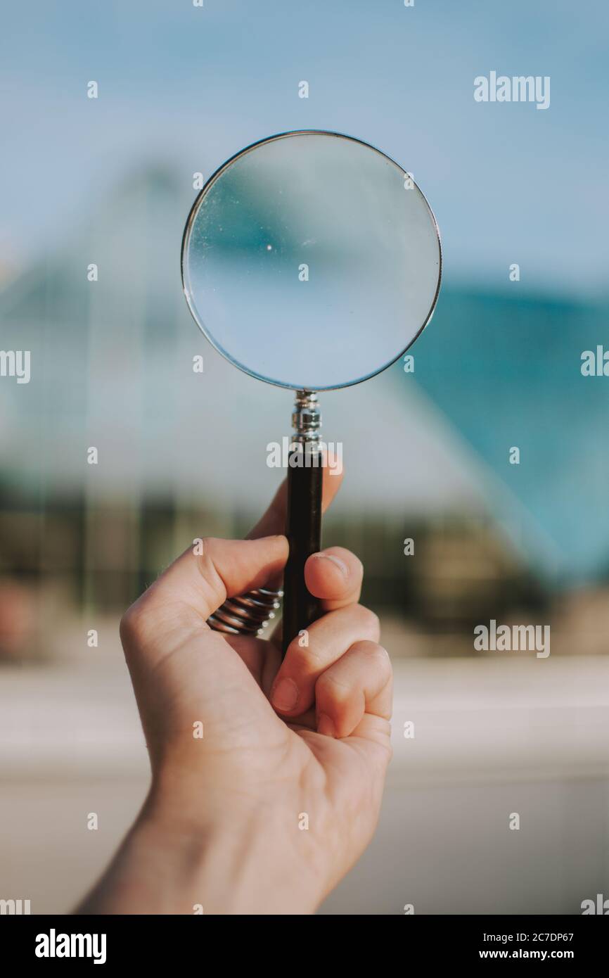 Vertical selective shot of a person holding a clear magnifying glass ...
