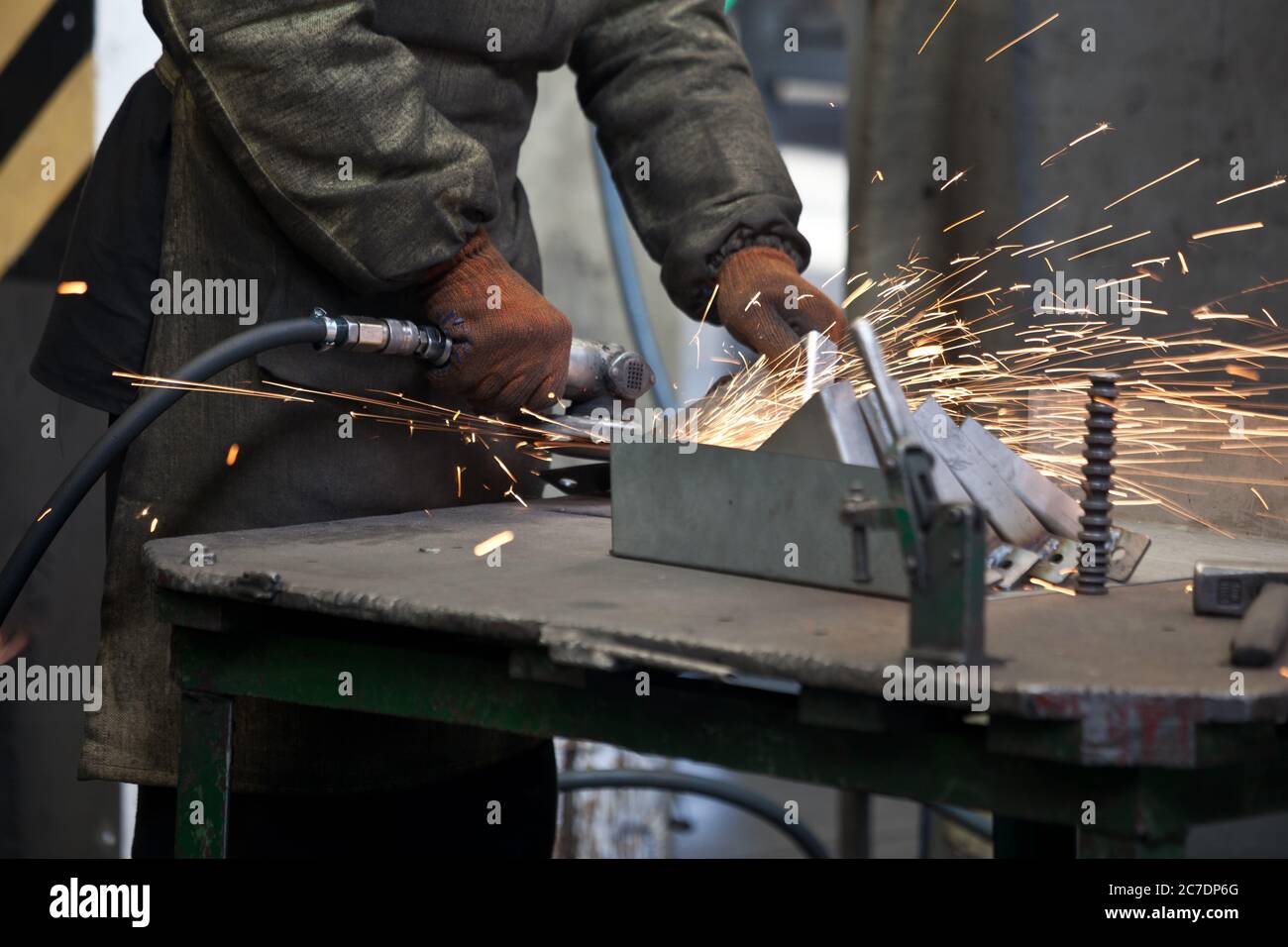 worker processing metal, lots of sparks, against factory industrial ...