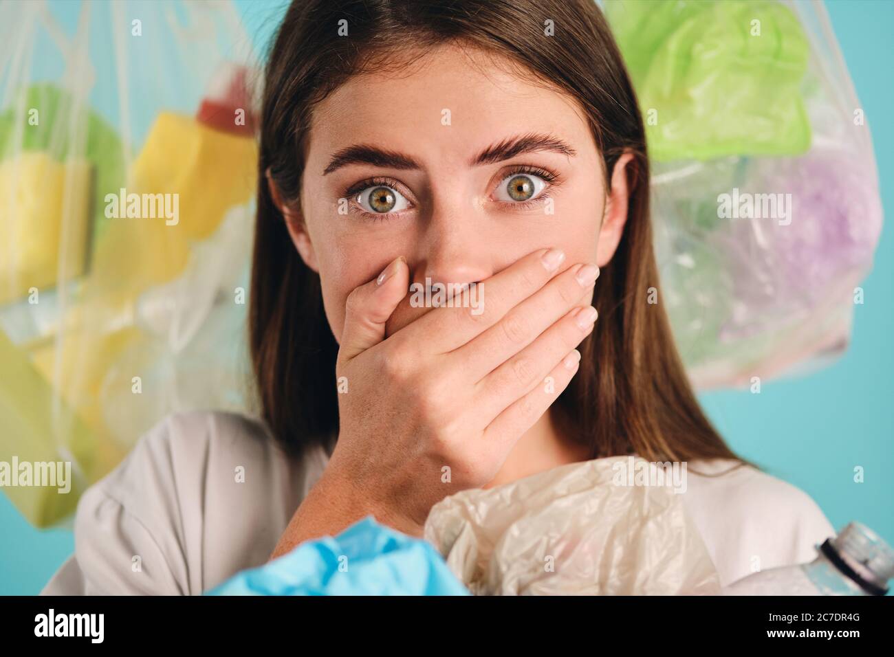 Portrait of shocked girl with plastic waste around amazedly looking in ...