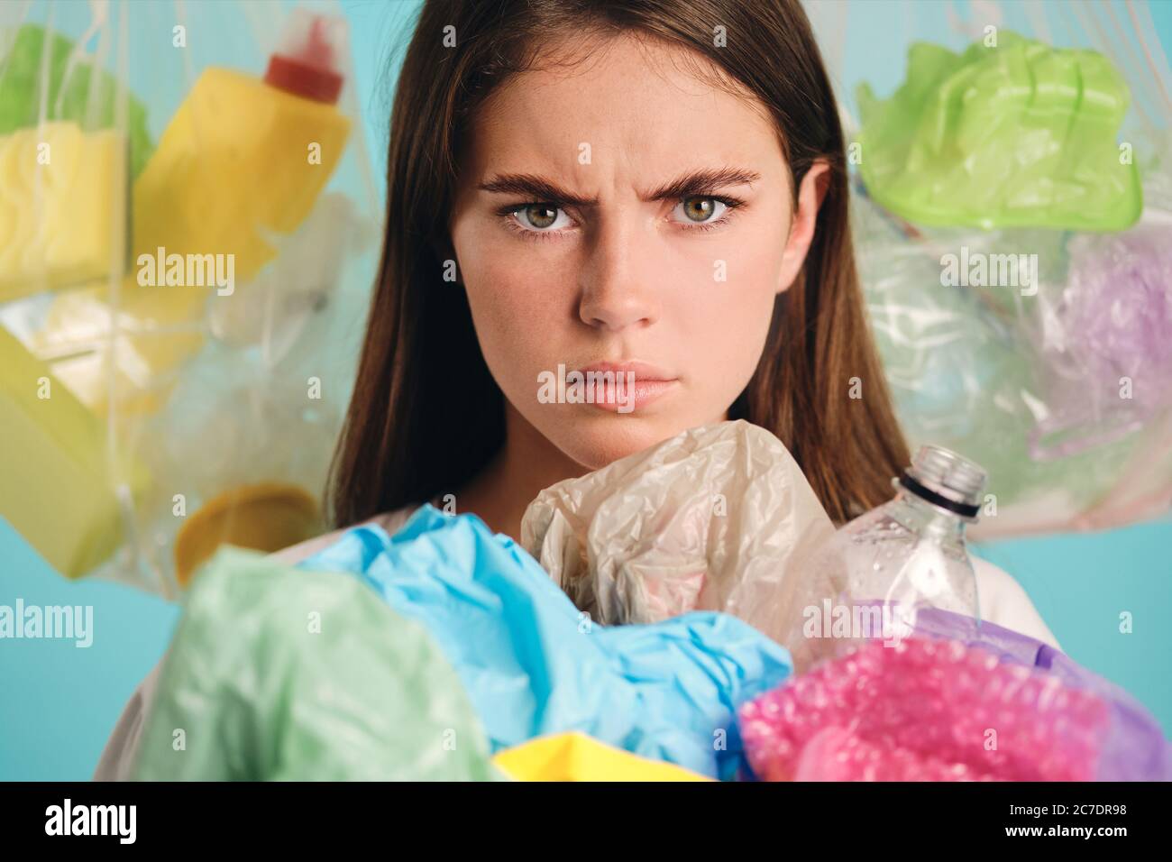 Aggressive girl with plastic waste around angrily looking in camera ...