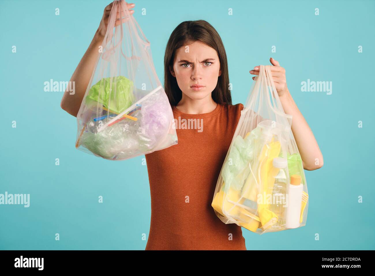 Angry girl in t-shirt holding eco bags with plastic waste wrathfully ...