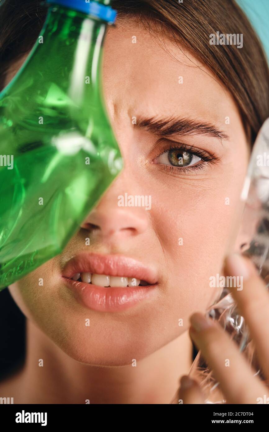 Close up upset girl covering face with empty plastic bottles ...