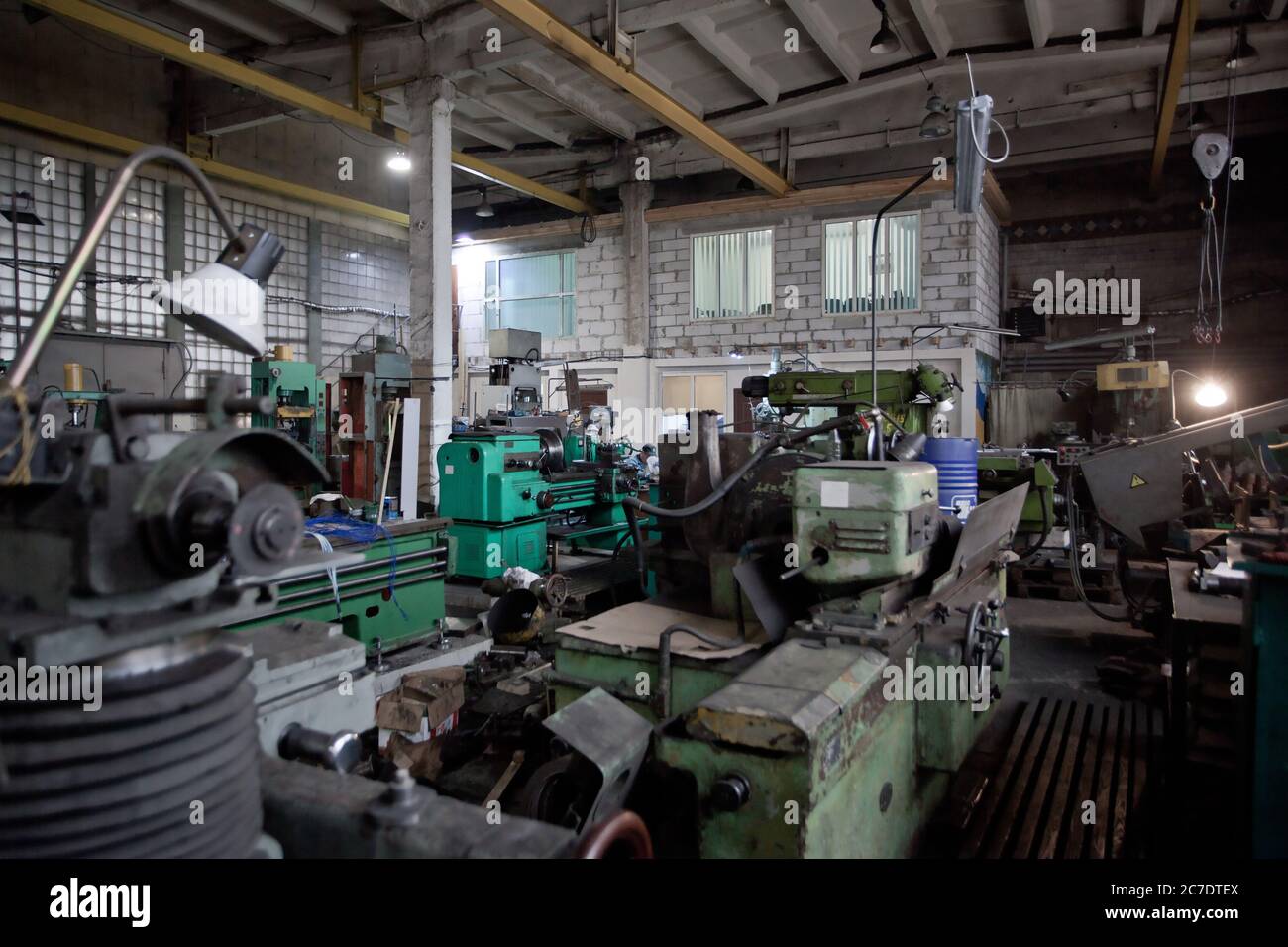 closeup of metallic lathe working against factory industrial interior ...