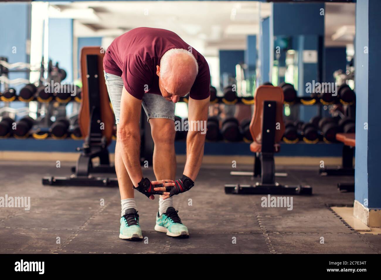 A portrait of bald senior man doing workout before training in the gym ...