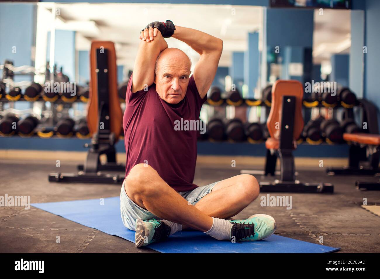 A portrait of bald senior man doing stretching after training in the ...