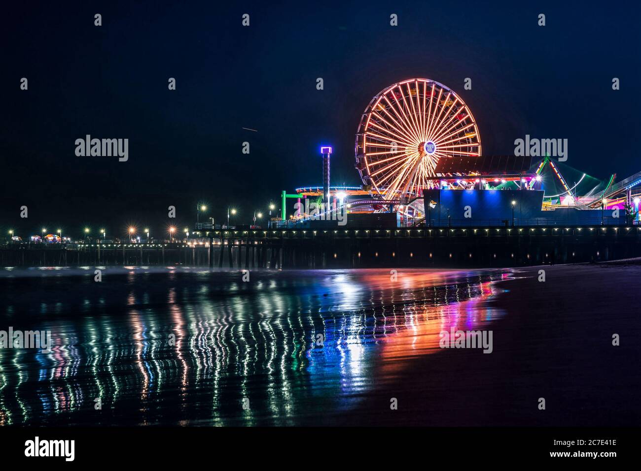 Horizontal nighttime shot of from a beach of an amusement park on with ...