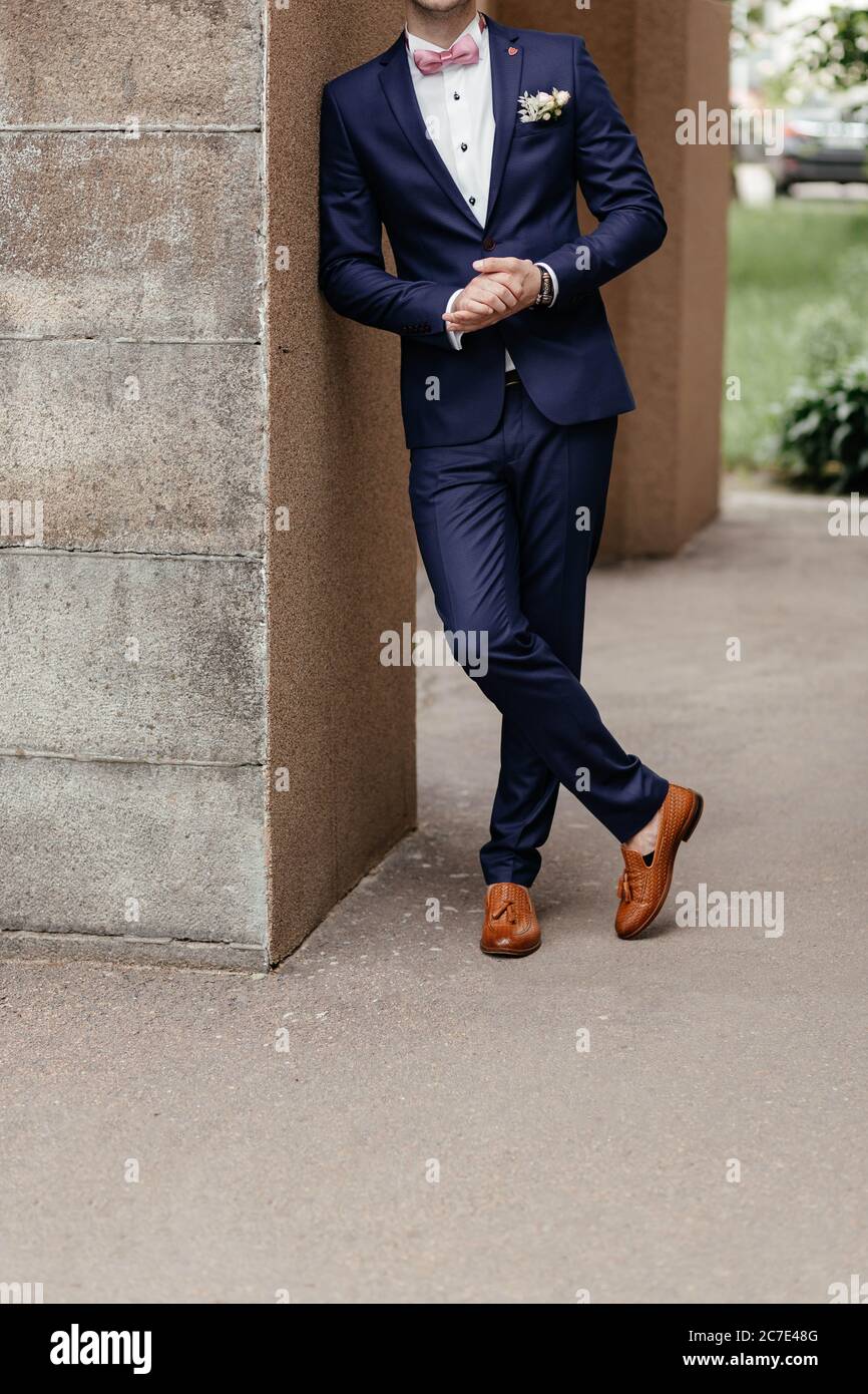 Faceless groom wearing the suit and bow tie standing cross-legged near ...