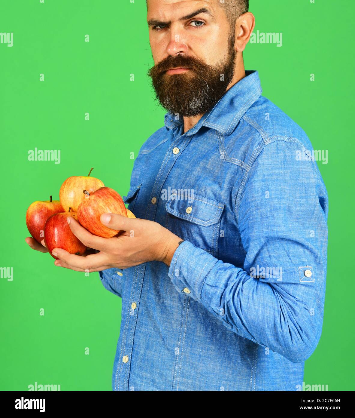 Guy presents homegrown harvest. Farmer with strict face and hands full ...
