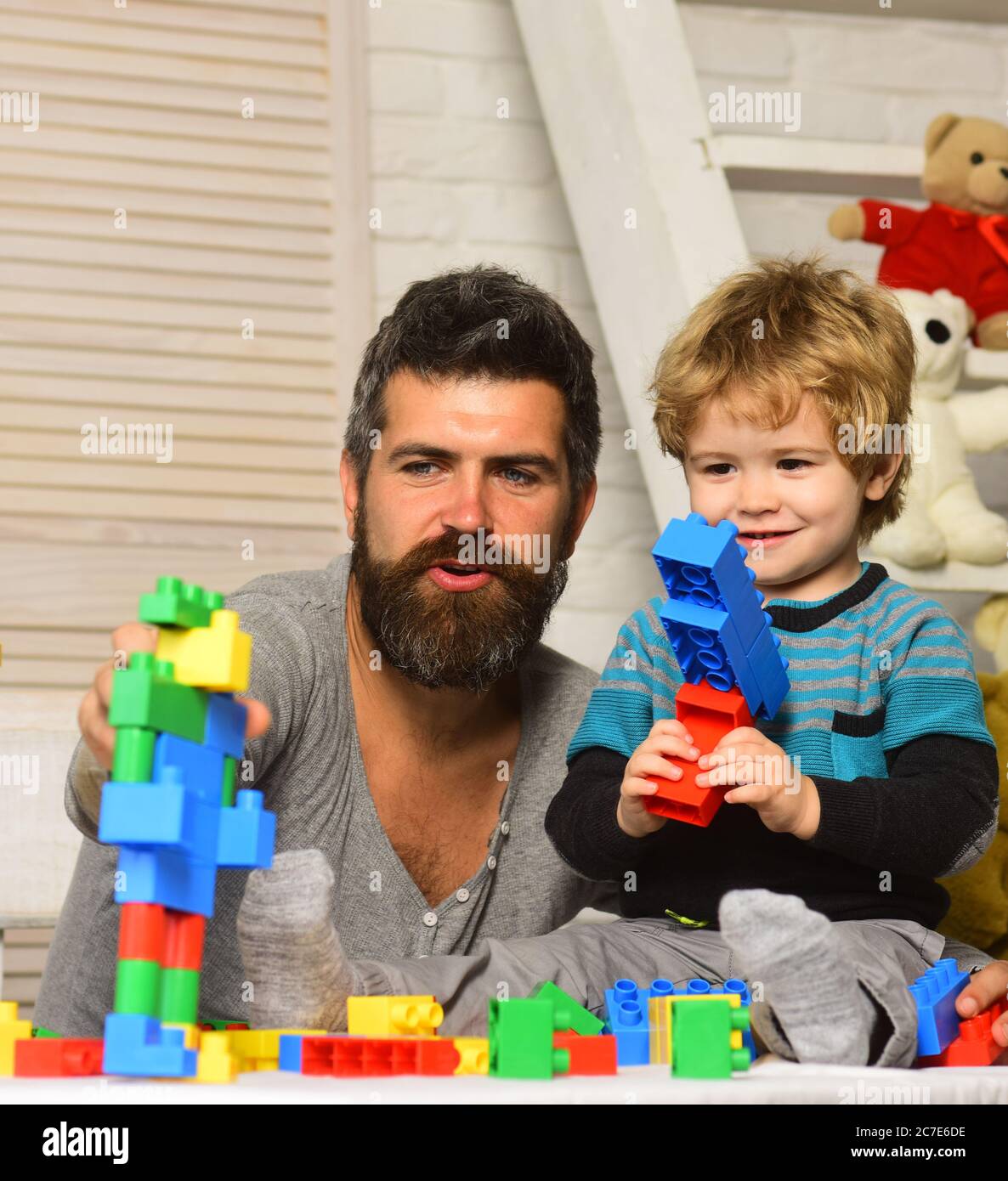 Father and son with happy faces create colorful constructions of toy ...