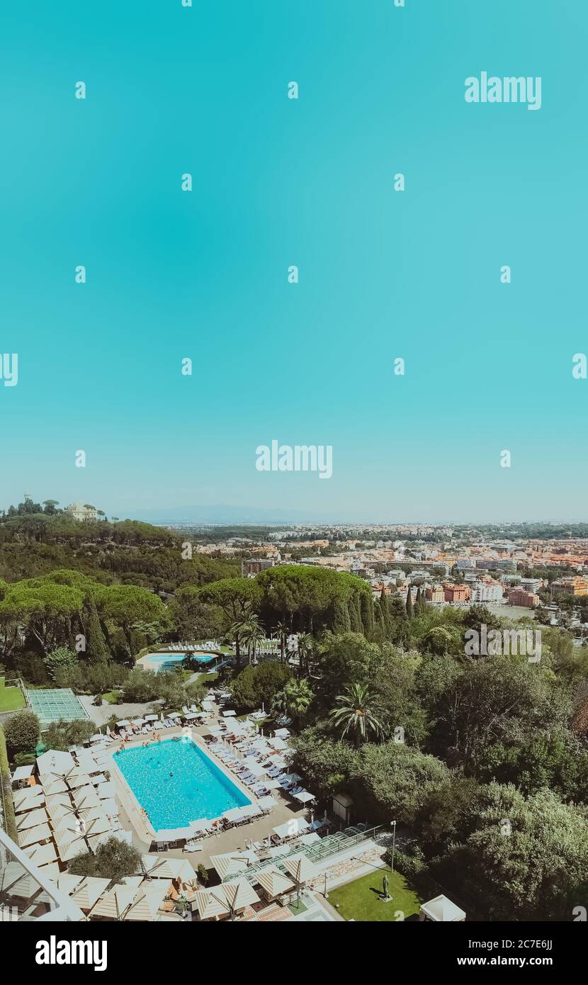 High angle vertical shot of a pool surrounded by trees with buildings ...