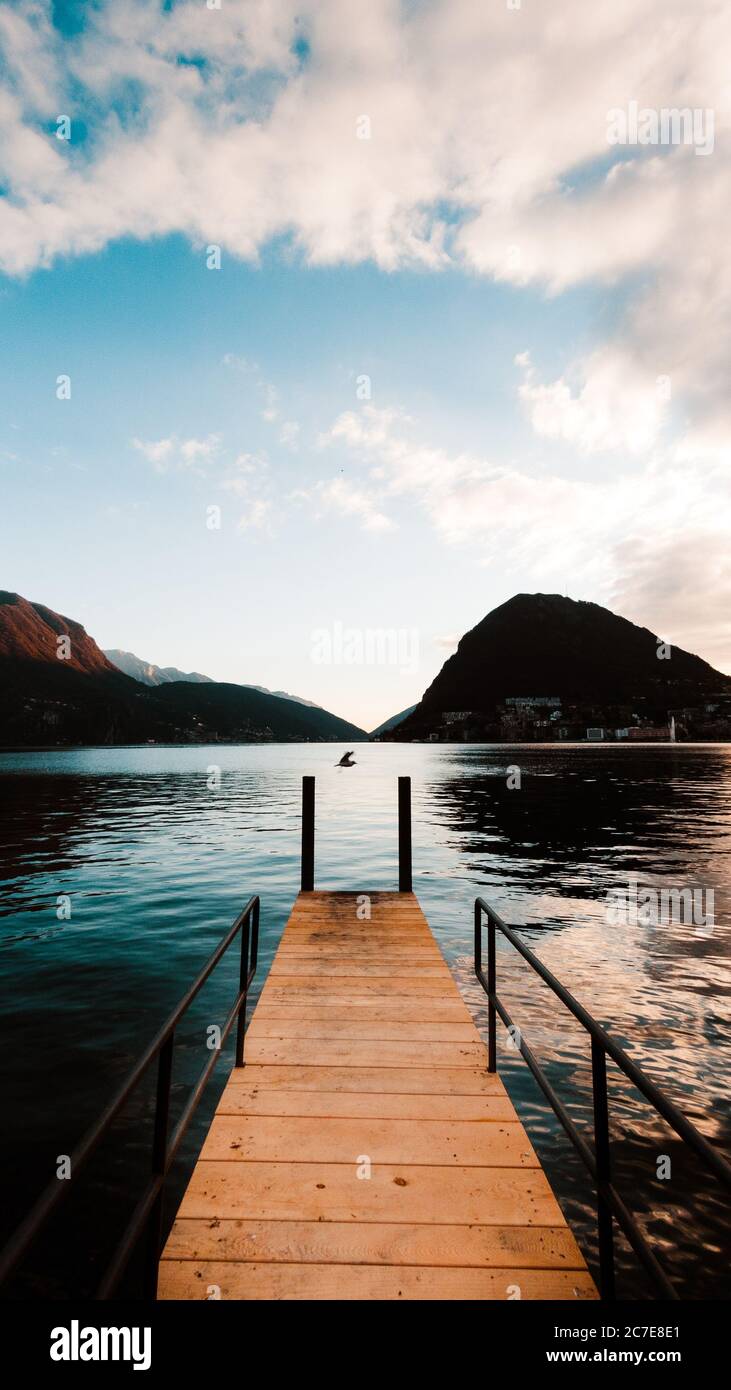 Vertical shot of a wooden dock near the sea surrounded by high hills ...