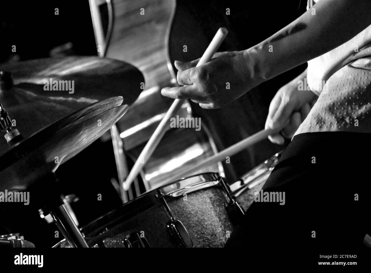 Horizontal greyscale shot of a drummer performing on the stage during a ...