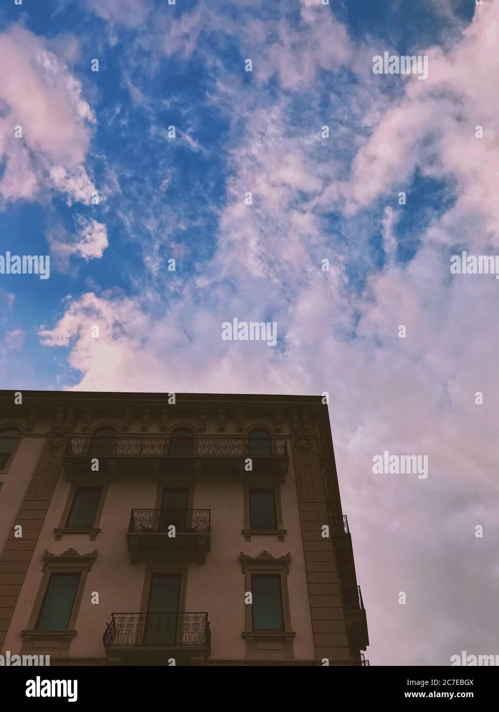 Vertical low angle shot of a concrete building under the breathtaking cloudy sky Stock Photo - Alamy