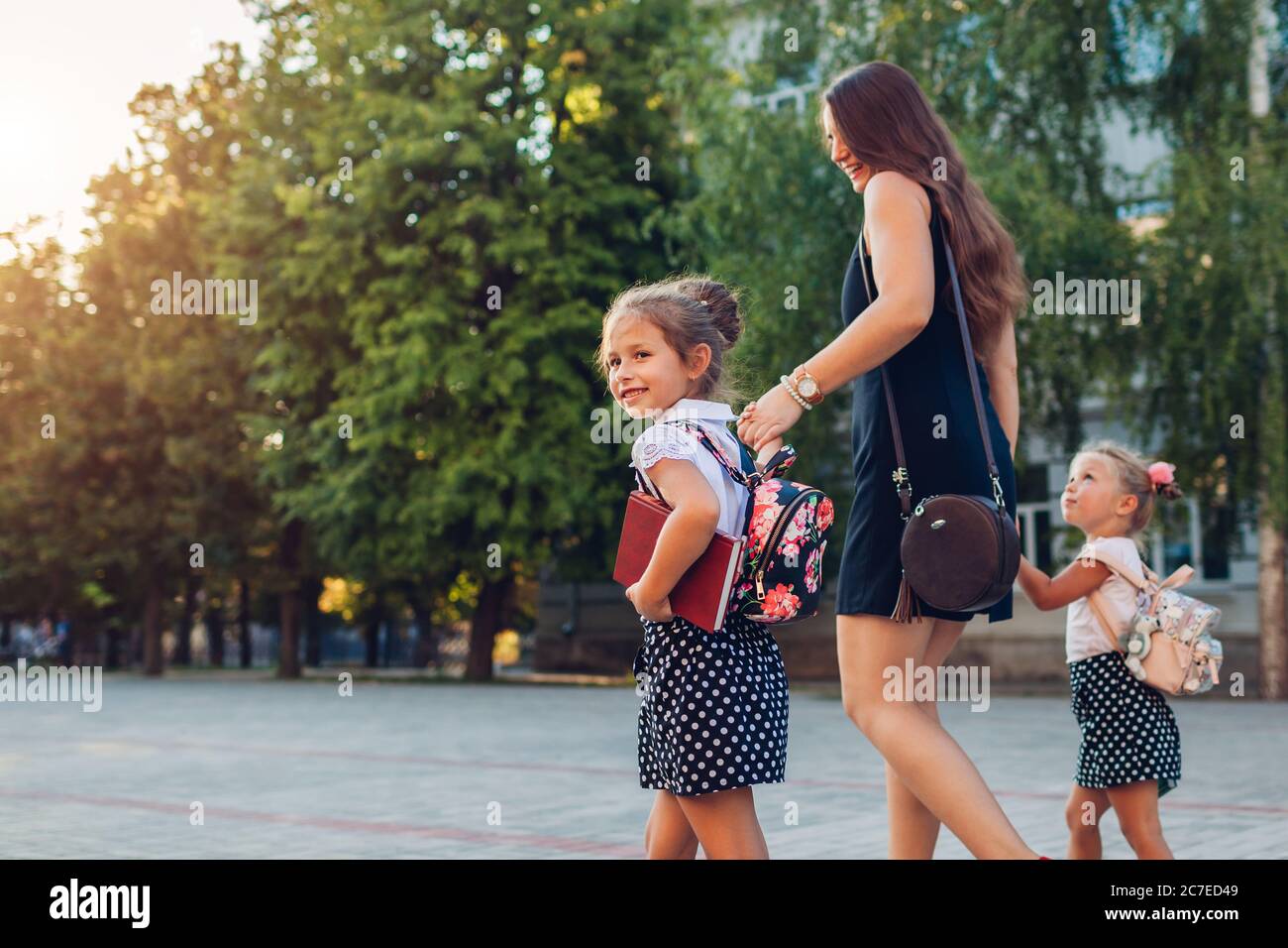 Mother meeting kids daughters after classes outdoors primary school ...