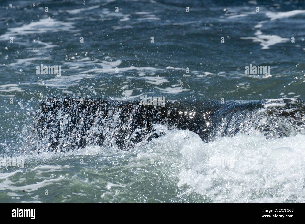 Water splashing over a rock in the atlantic ocean, creating a beautiful ...