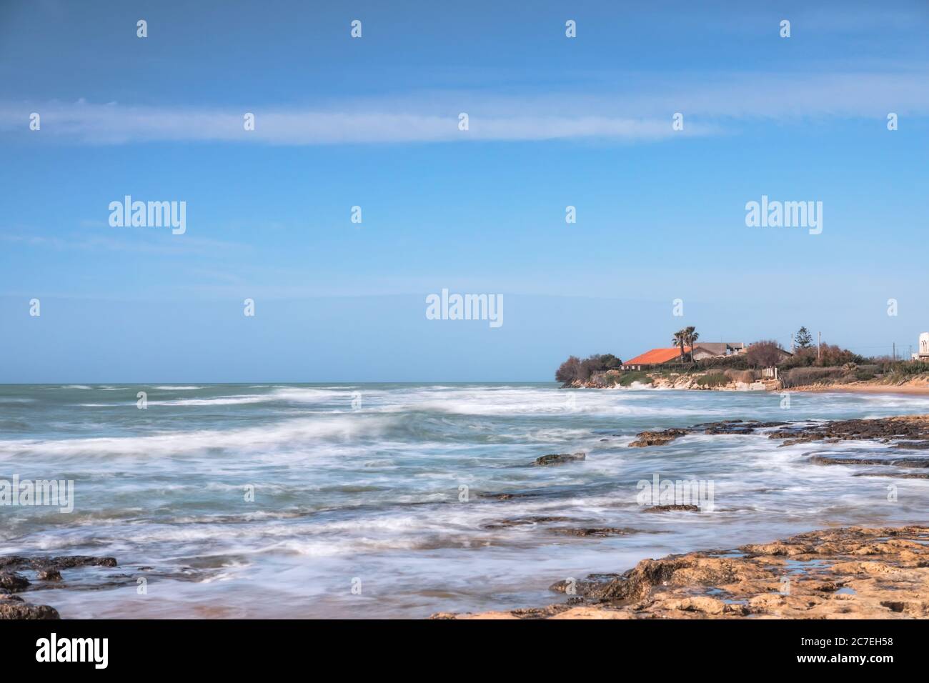 Horizontal shot of the beautiful sea with crazy waves and a house on ...