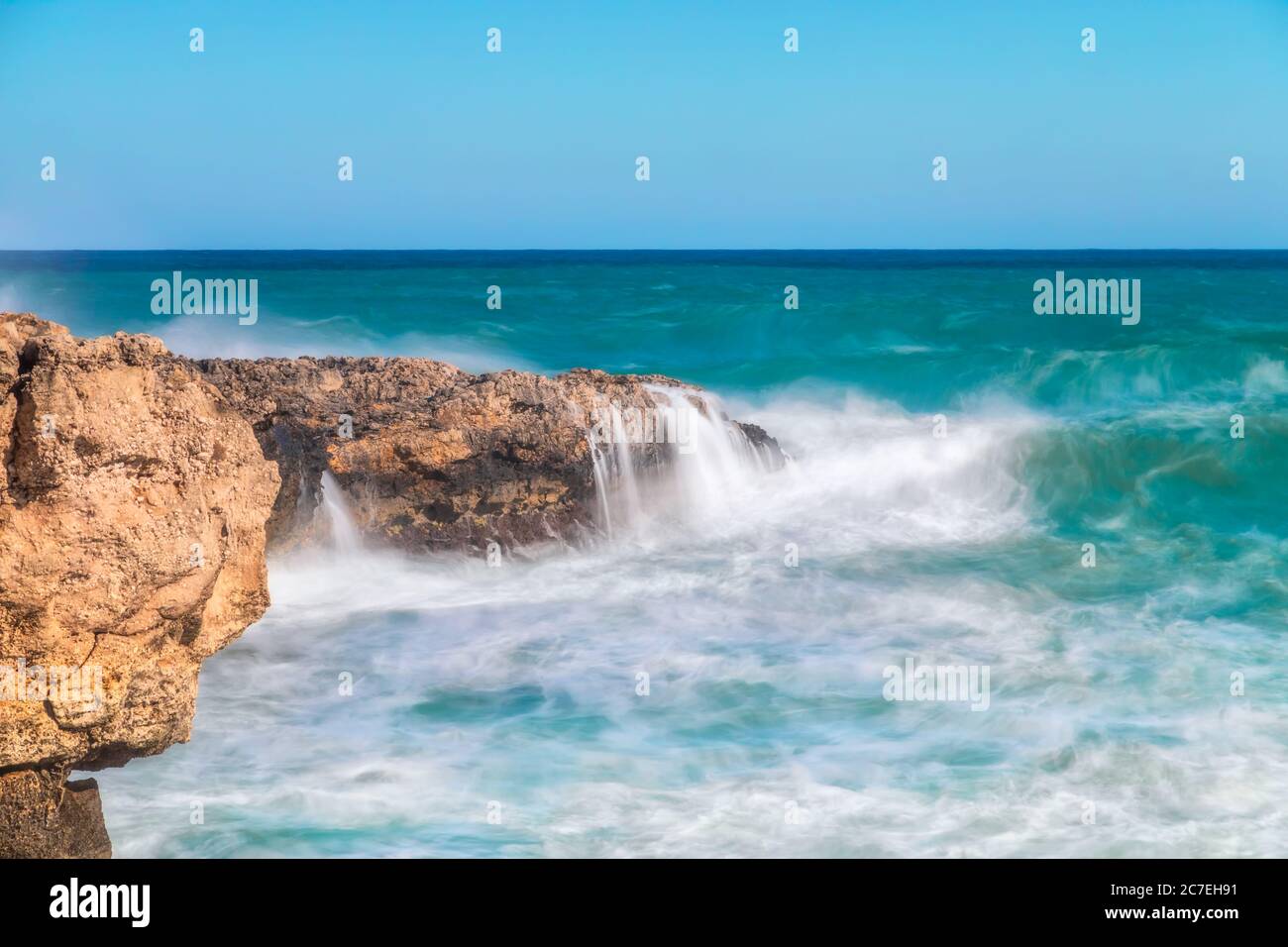 Horizontal shot of huge rocks in the ocean and the beautiful waves of ...