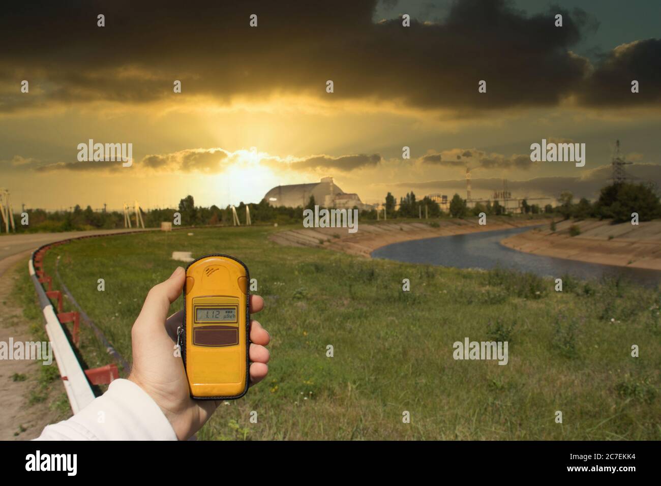 Hand holding a yellow dosimeter showing high radiation, metal ...