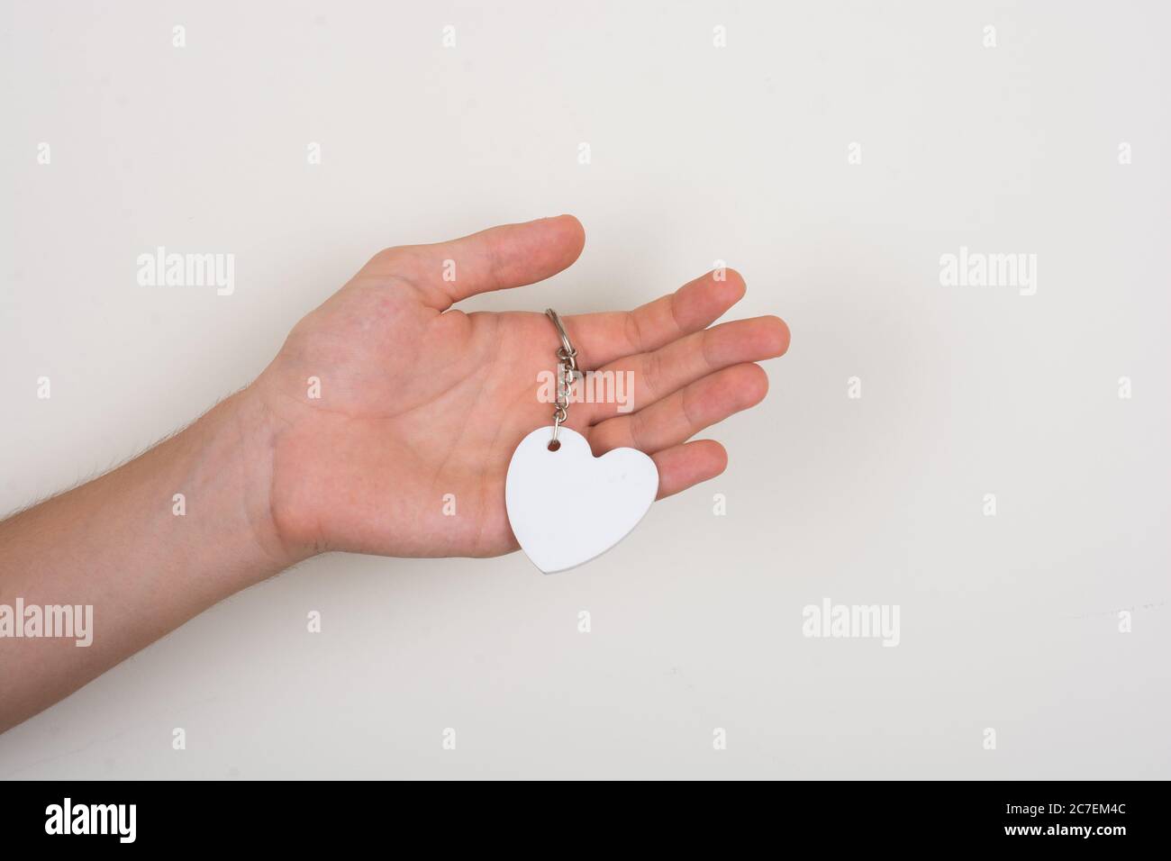 Heart shaped white object in hand on white background Stock Photo - Alamy