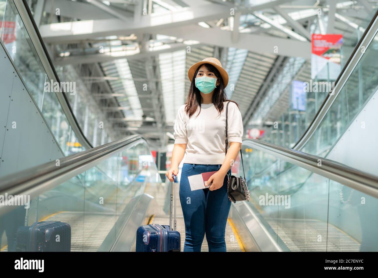 Asian traveler woman with luggage wearing face mask looking outside ...