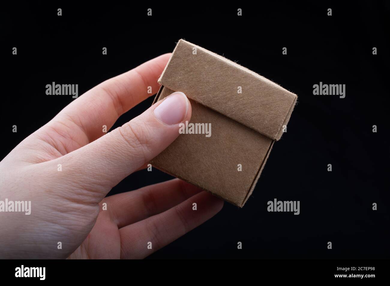 Hand holding a brown cardboard box on black backgrounds Stock Photo - Alamy