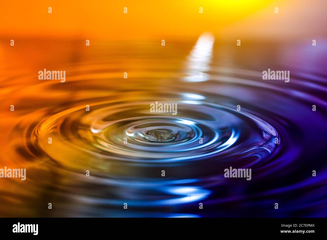 Macro photo of water drops falling into a pool of water, causing a ...