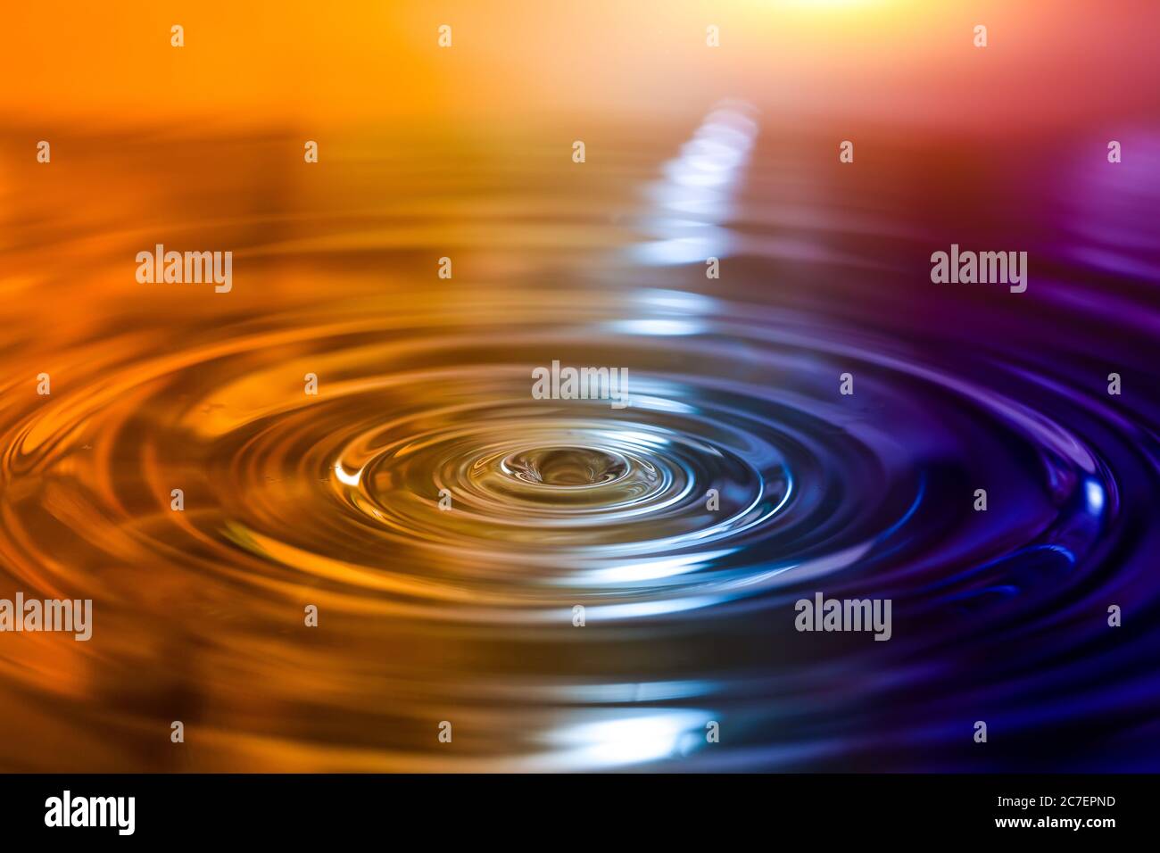 Macro photo of water drops falling into a pool of water, causing a ...