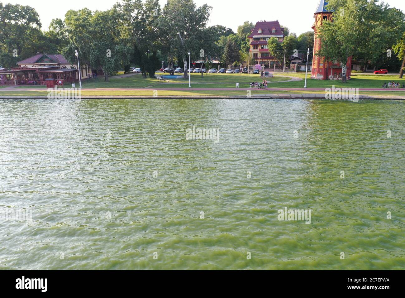 Close shot of people walking in the park near buildings and water at ...
