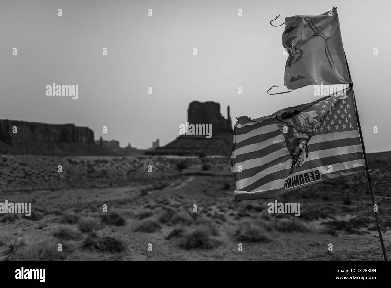 Greyscale shot of flag of the US with Geronimo print in front of rock ...