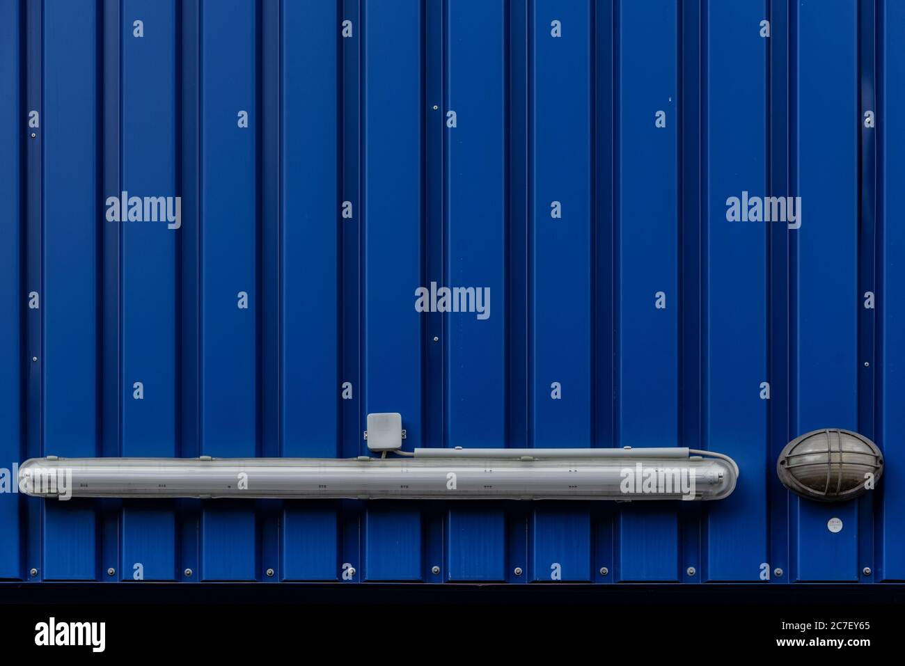 Horizontal closeup of a blue metallic wall with a tube fluorescent ...