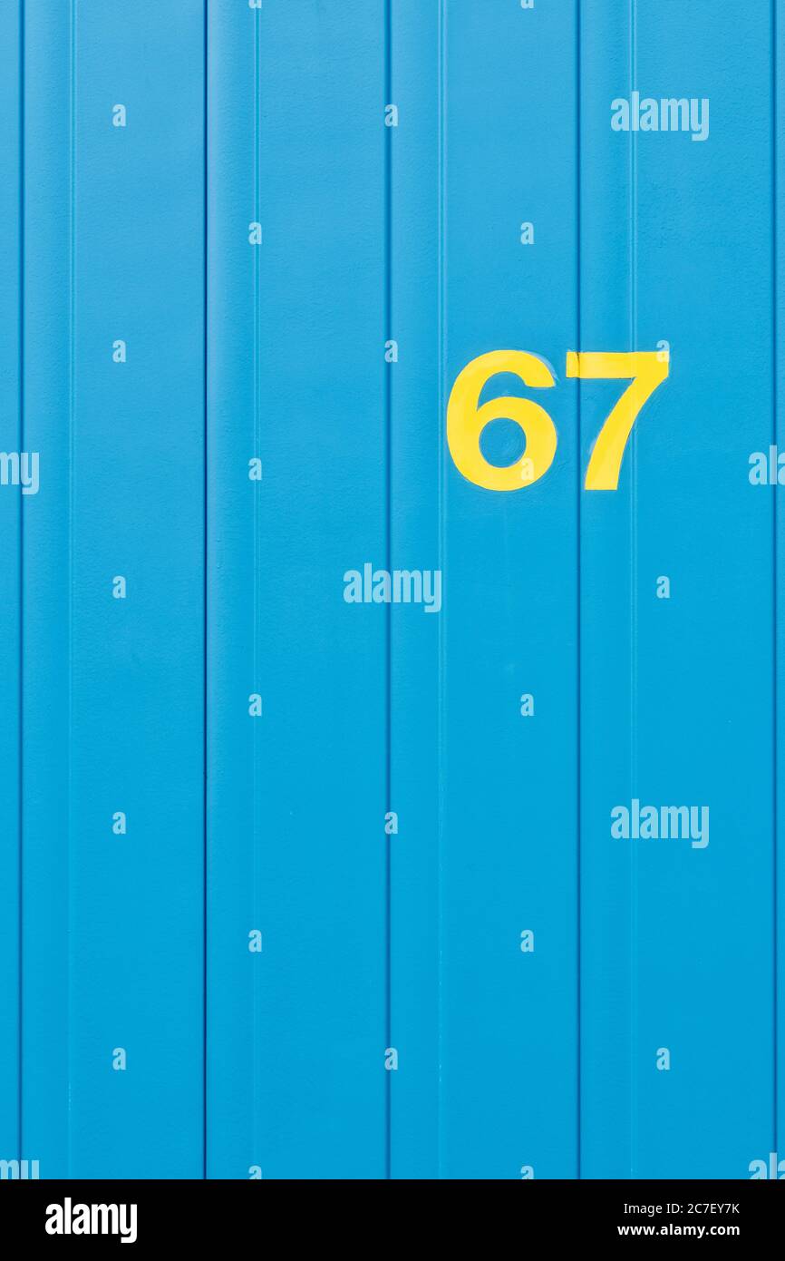 Vertical shot of a blue wall with the number 67 written on it in yellow ...