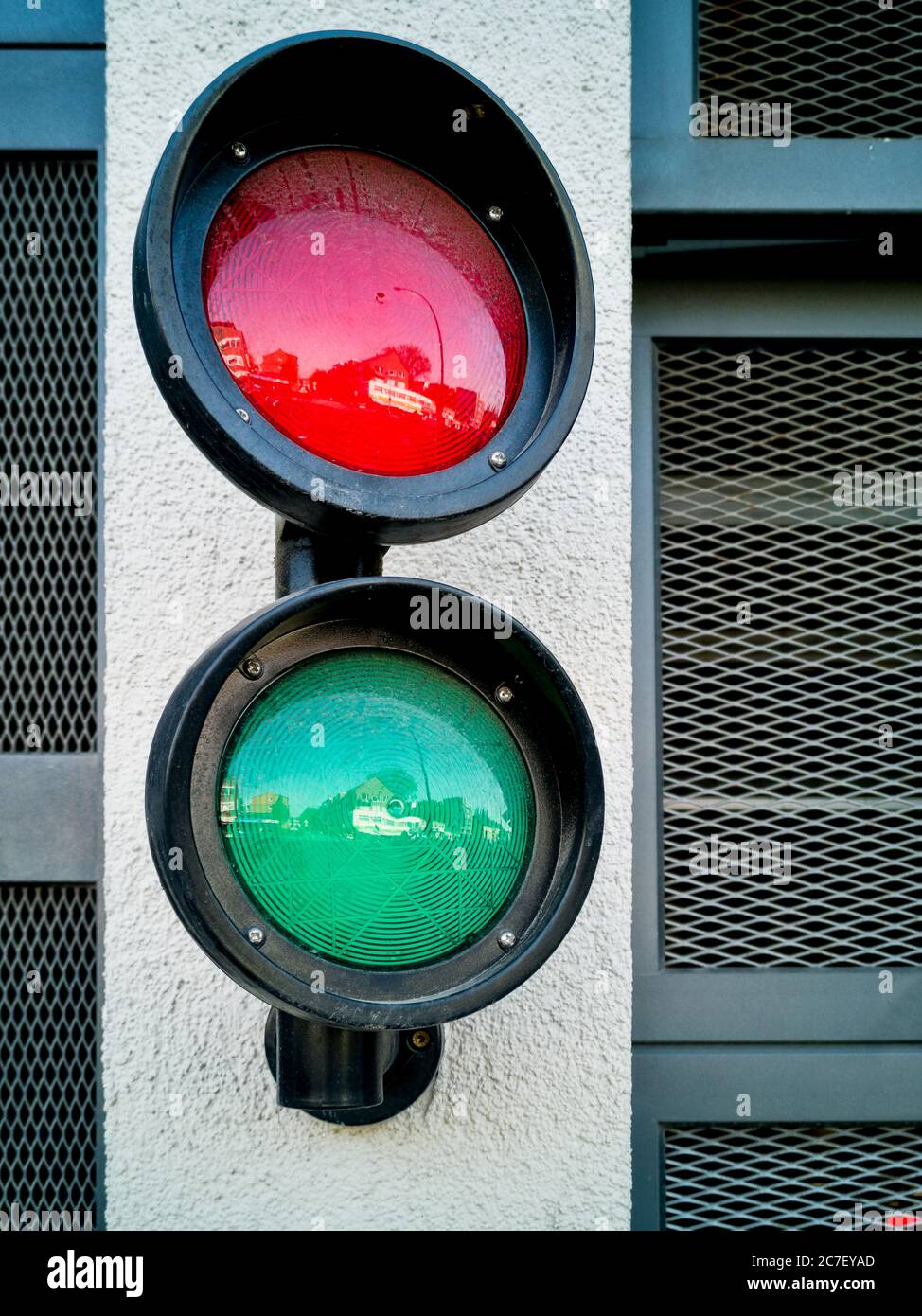 Vertical closeup of a red and green traffic light on a white wall ...