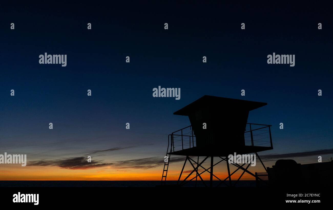 Horizontal shot of a beach watchtower in silhouette during golden hour ...