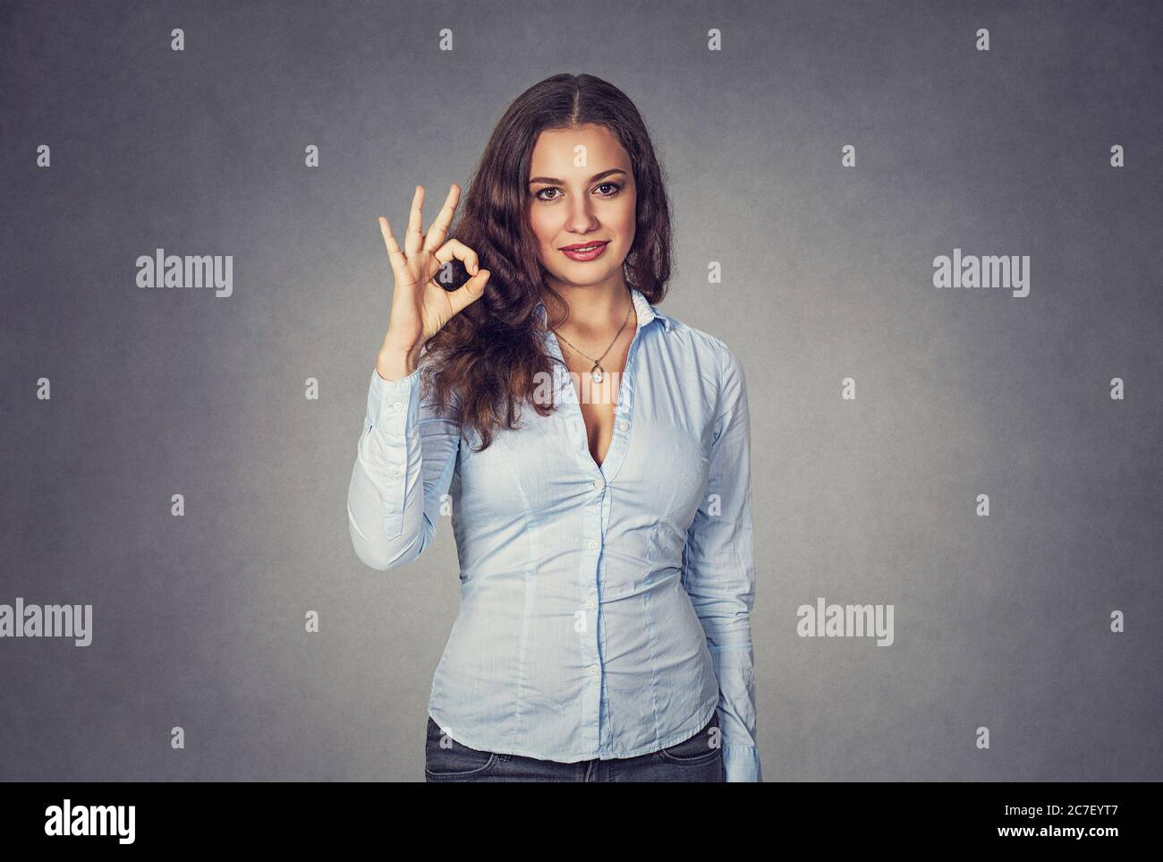 Happy woman showing ok sign gesture with hand isolated on studio gray ...